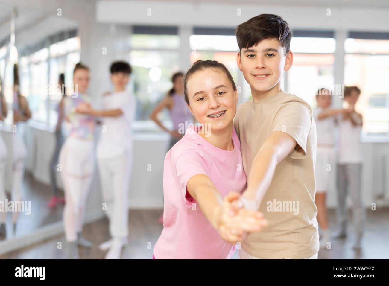 Group of positive teenagers learning to dance tango in dance studio ...