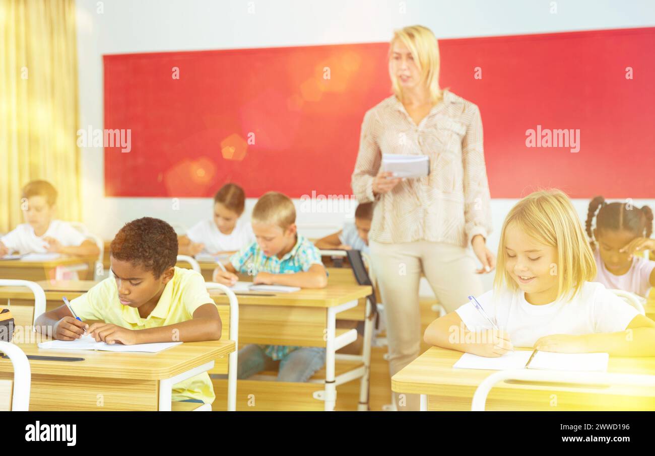 Teacher controlling learning process in primary school Stock Photo - Alamy