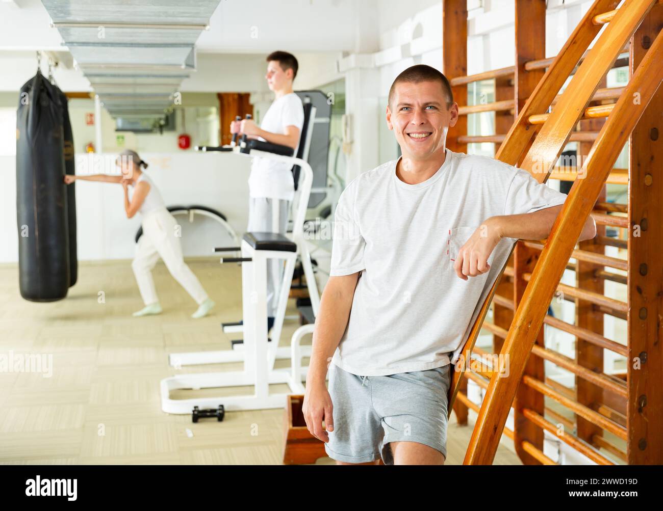 Positive man standing at ladder in gym Stock Photo - Alamy