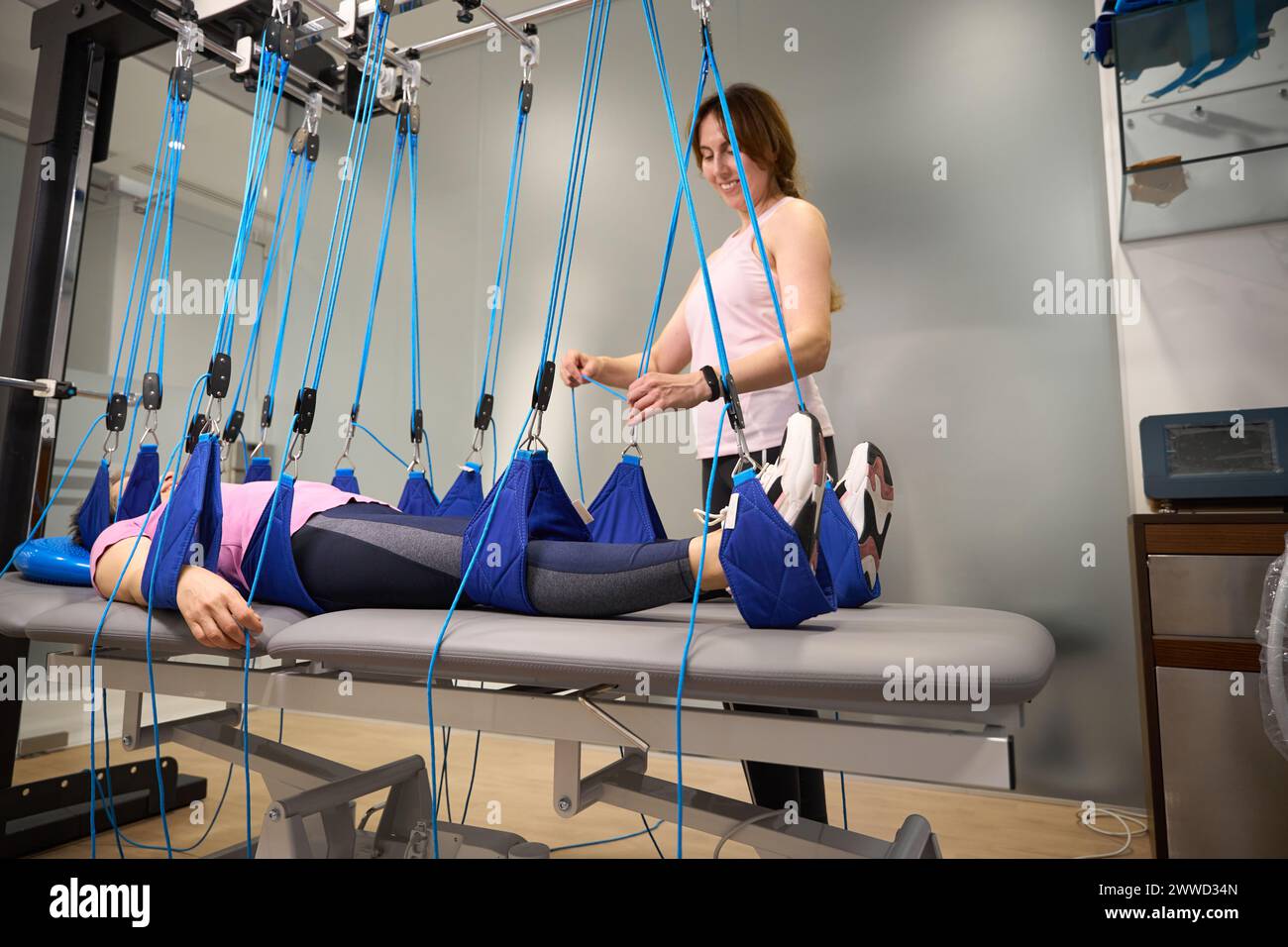 Young trainer preparing suspension medical ropes for hanging of woman ...