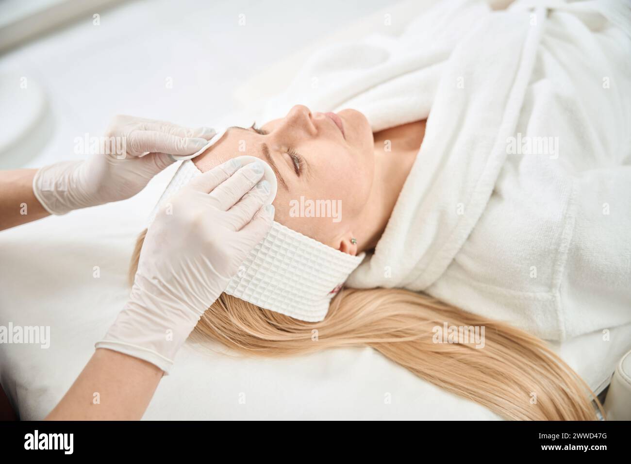 Cosmetologist cleaning female face from make-up, applying pore ...