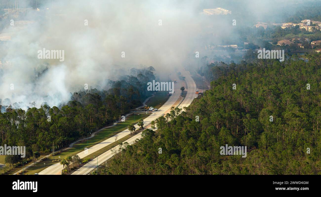 Aerial view of fire department firetrucks extinguishing wildfire ...