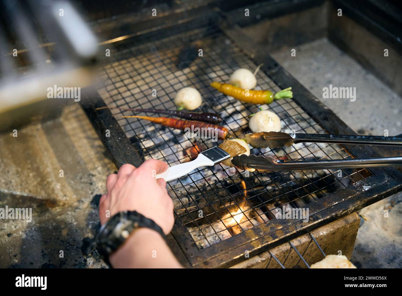 Partial male chef smearing onion and frying vegetables in burning fire ...