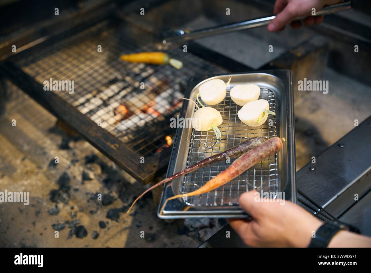 Male chef smearing onion with brush and frying vegetables in burning ...