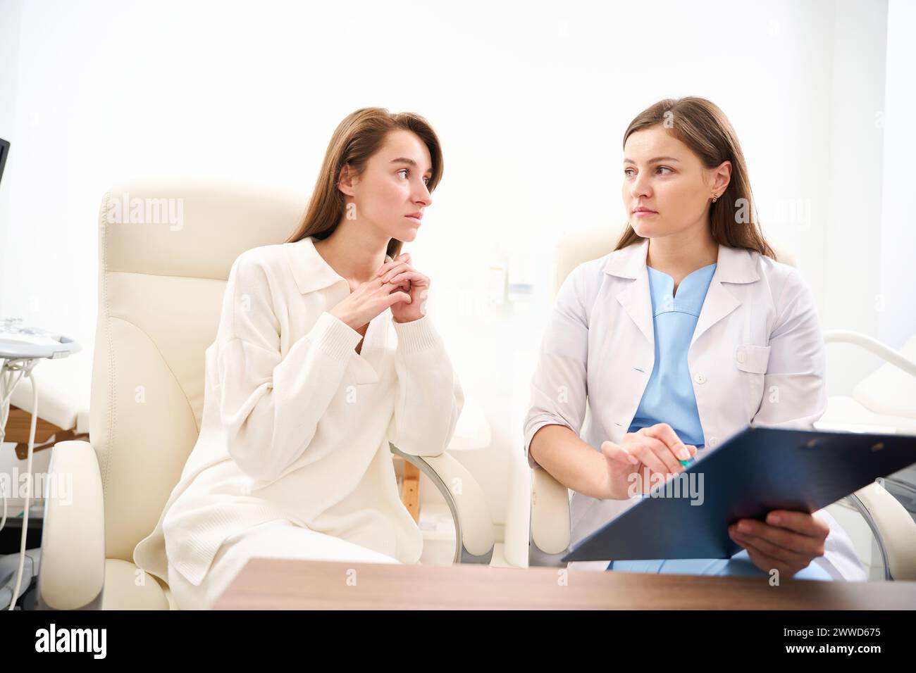 Female caucasian doctor showing to young tense woman her examining results Stock Photo - Alamy