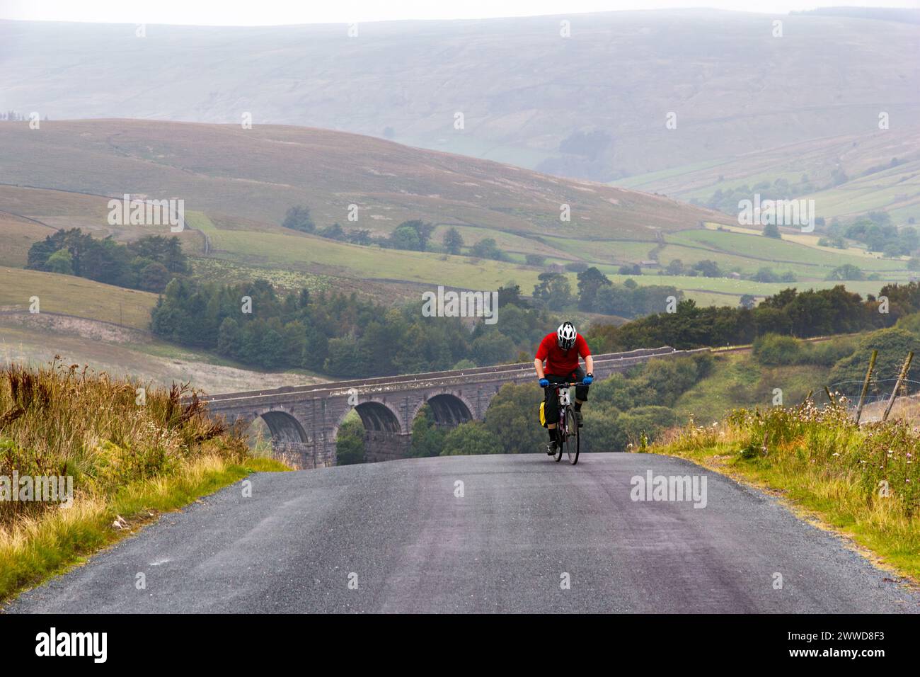 Tired cyclist pedals on at the top of a very steep hill in the ...