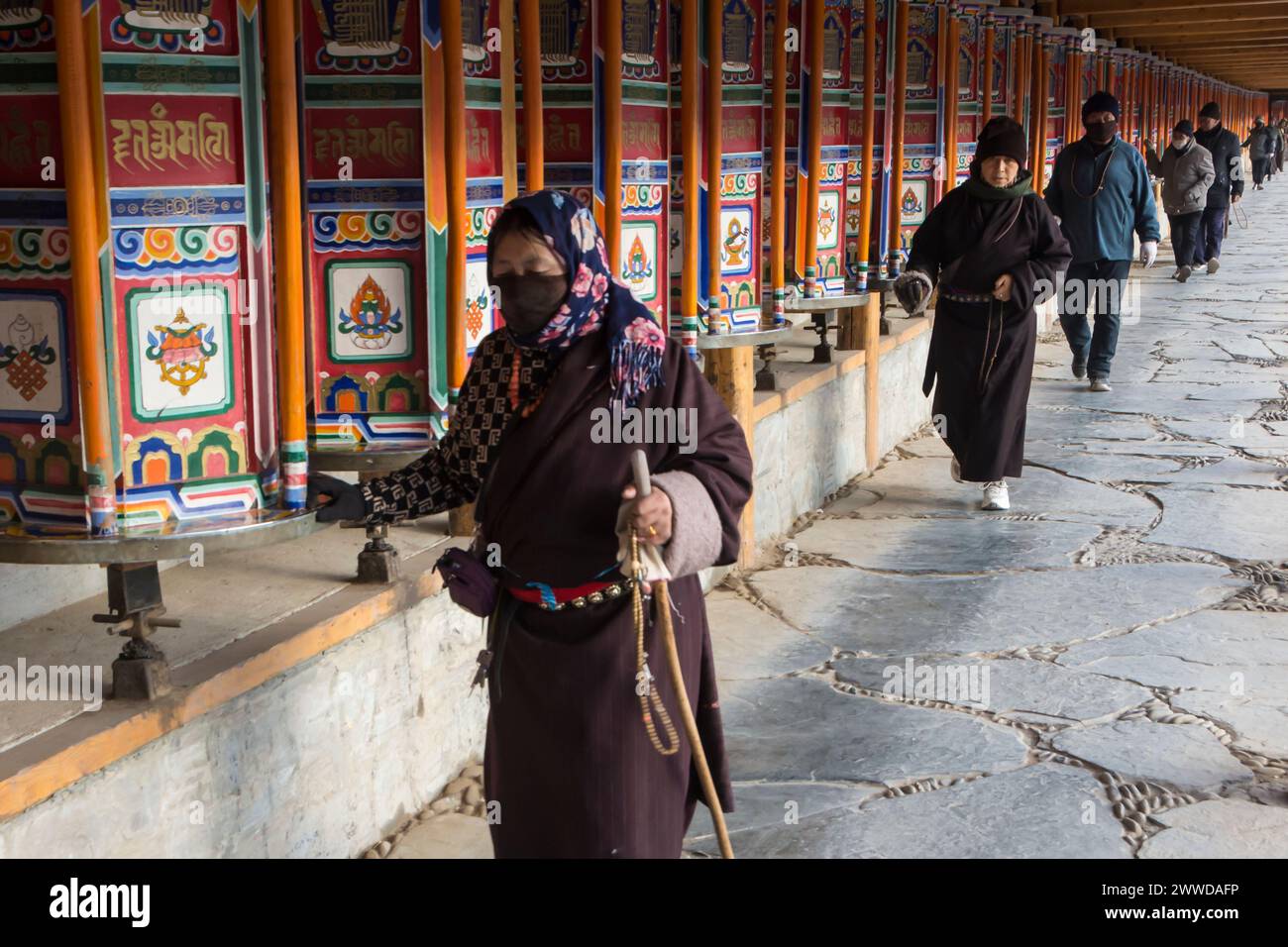 Pilgrims walking along the hundreds of prayer wheels of the 4 km ...