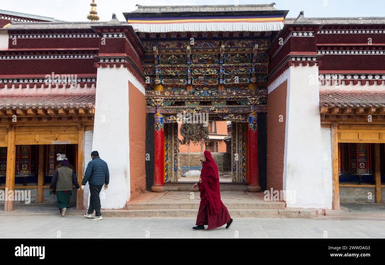 Monk passes a colorful entrance of a temple while performing the kora ...