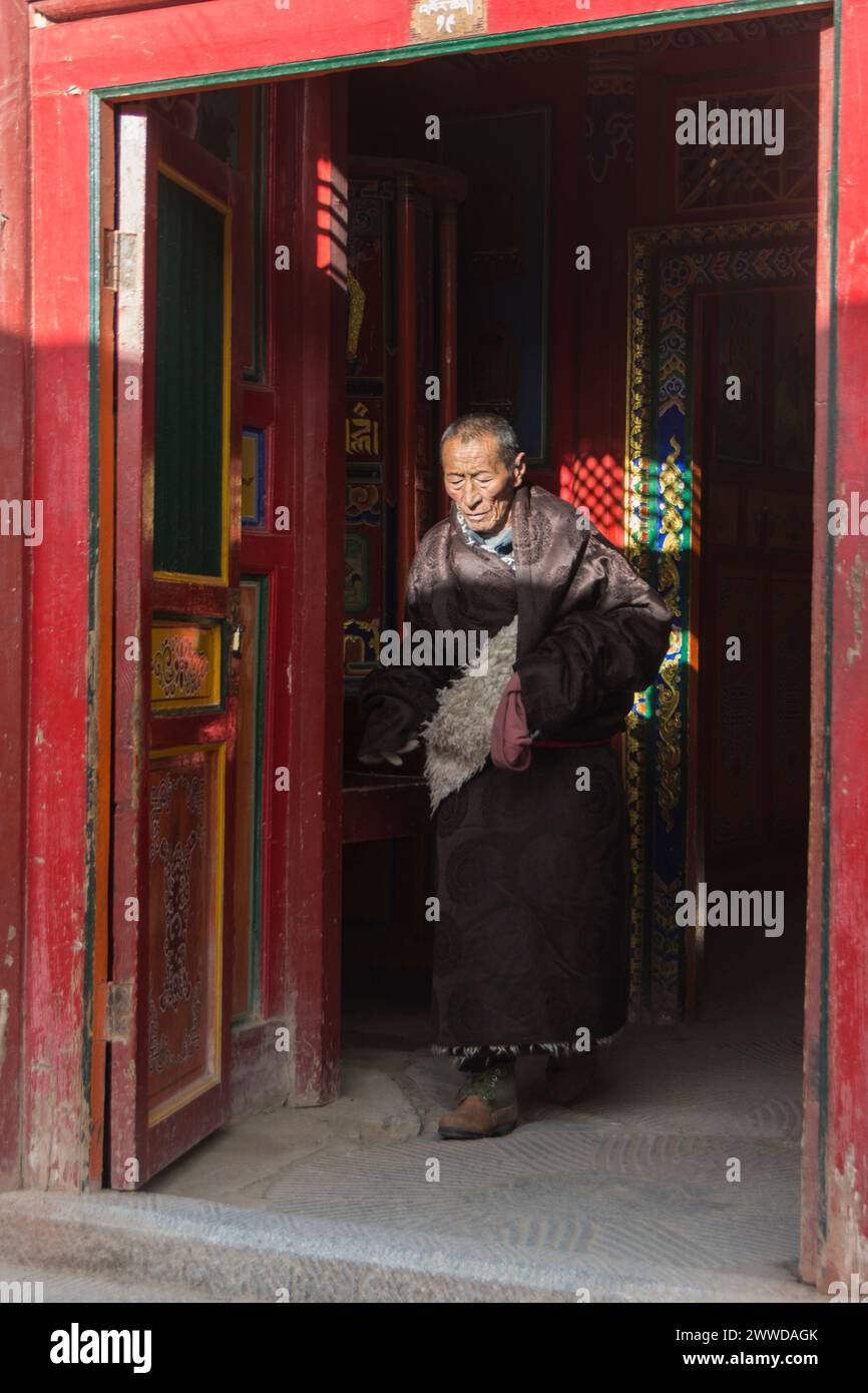 Elderly male pilgrim, face caught in sunlight, leaving a room with a ...