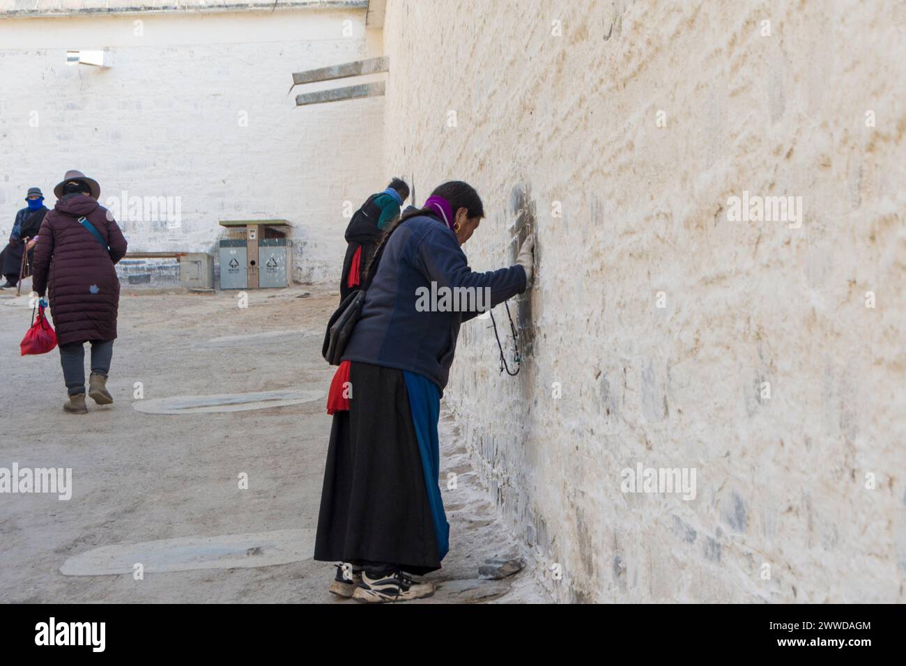 Female pilgrim pressing her head against the wall of a temple while ...