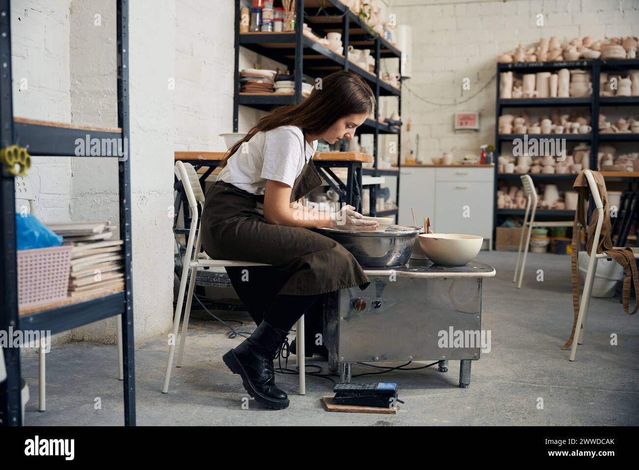Woman making pot using pottery wheel in creative studio Stock Photo - Alamy