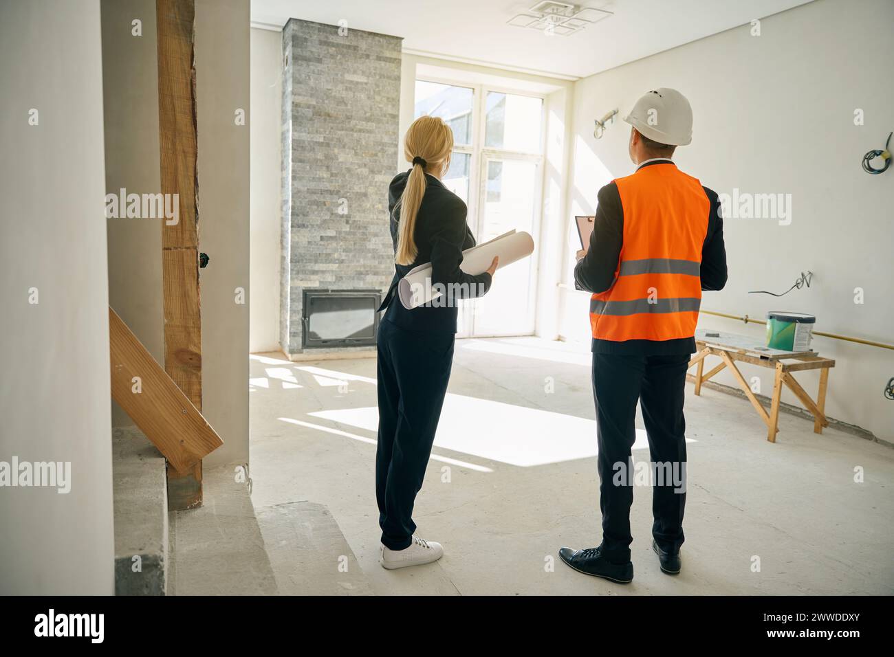 Female client and male engineer standing in room under construction ...