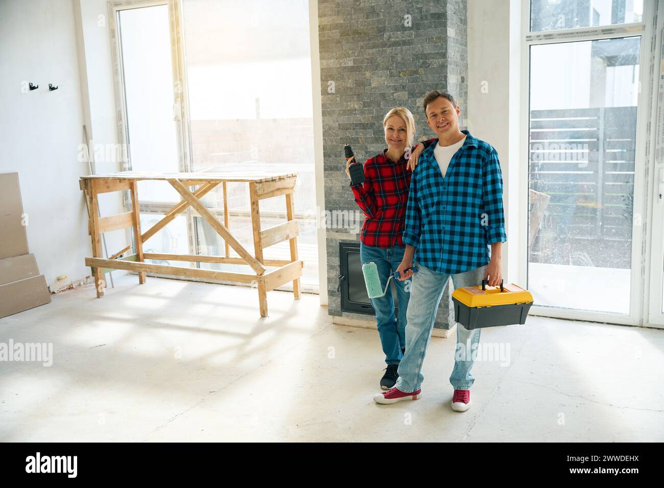 Happy couple standing and holding construction tools in hands Stock ...
