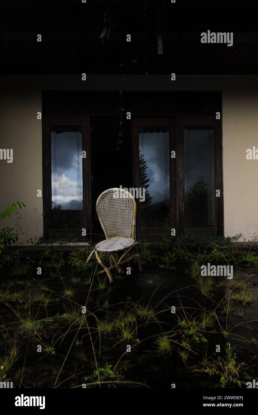 An abandoned wicker chair sits forlornly on a neglected patio ...