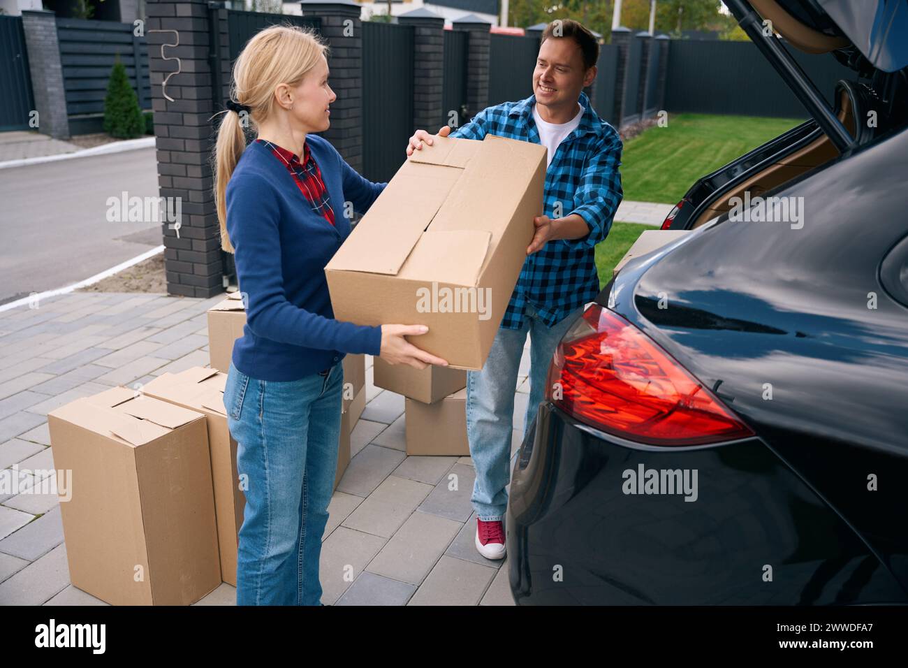 Lady standing and helping man to load boxes in car Stock Photo - Alamy