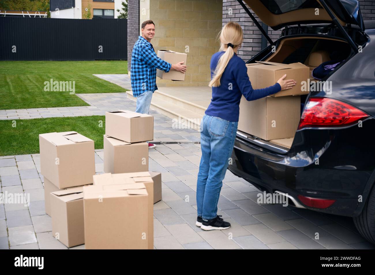 Couple unloading boxes from car trunk during house move Stock Photo - Alamy