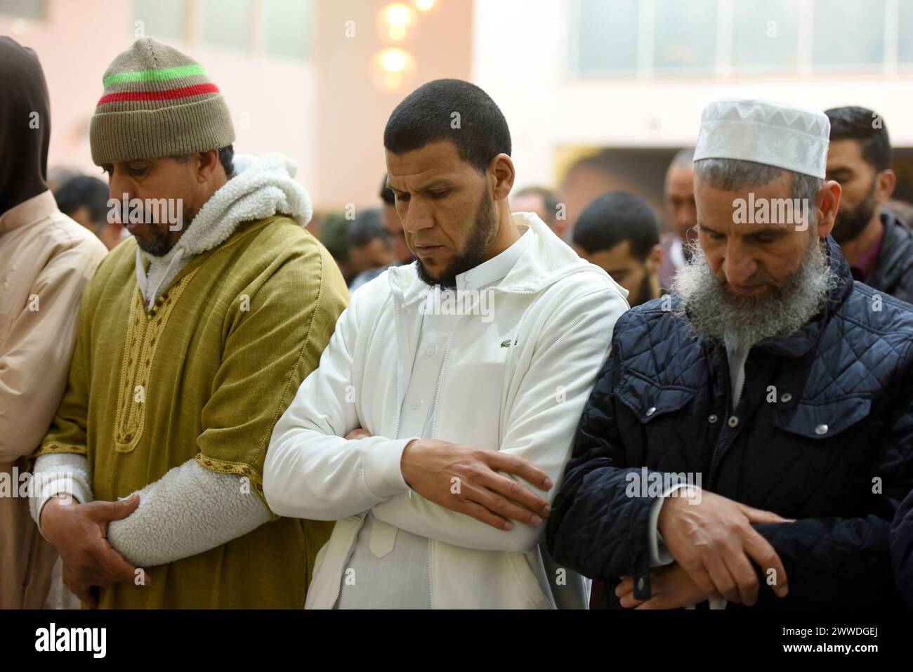 Several Muslim men pray standing with their arms crossed during the ...