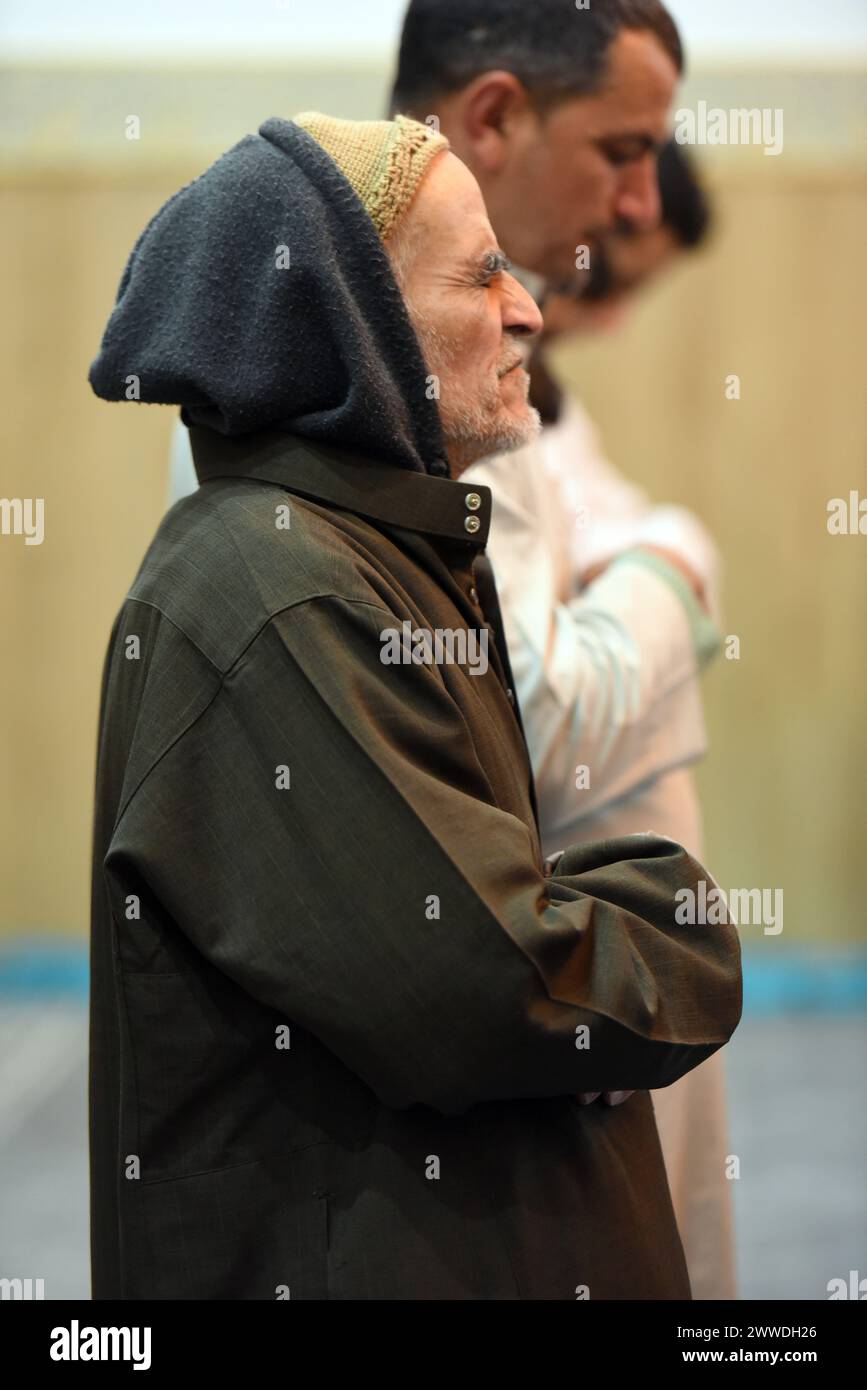Several Muslim men pray standing with their arms crossed during the ...