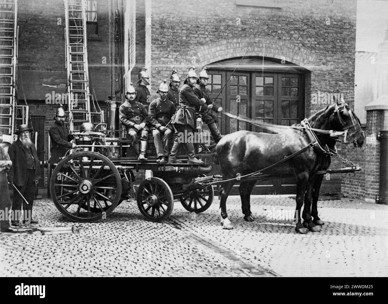 Photograph of a fire engine manned by seven firemen with a pair of ...