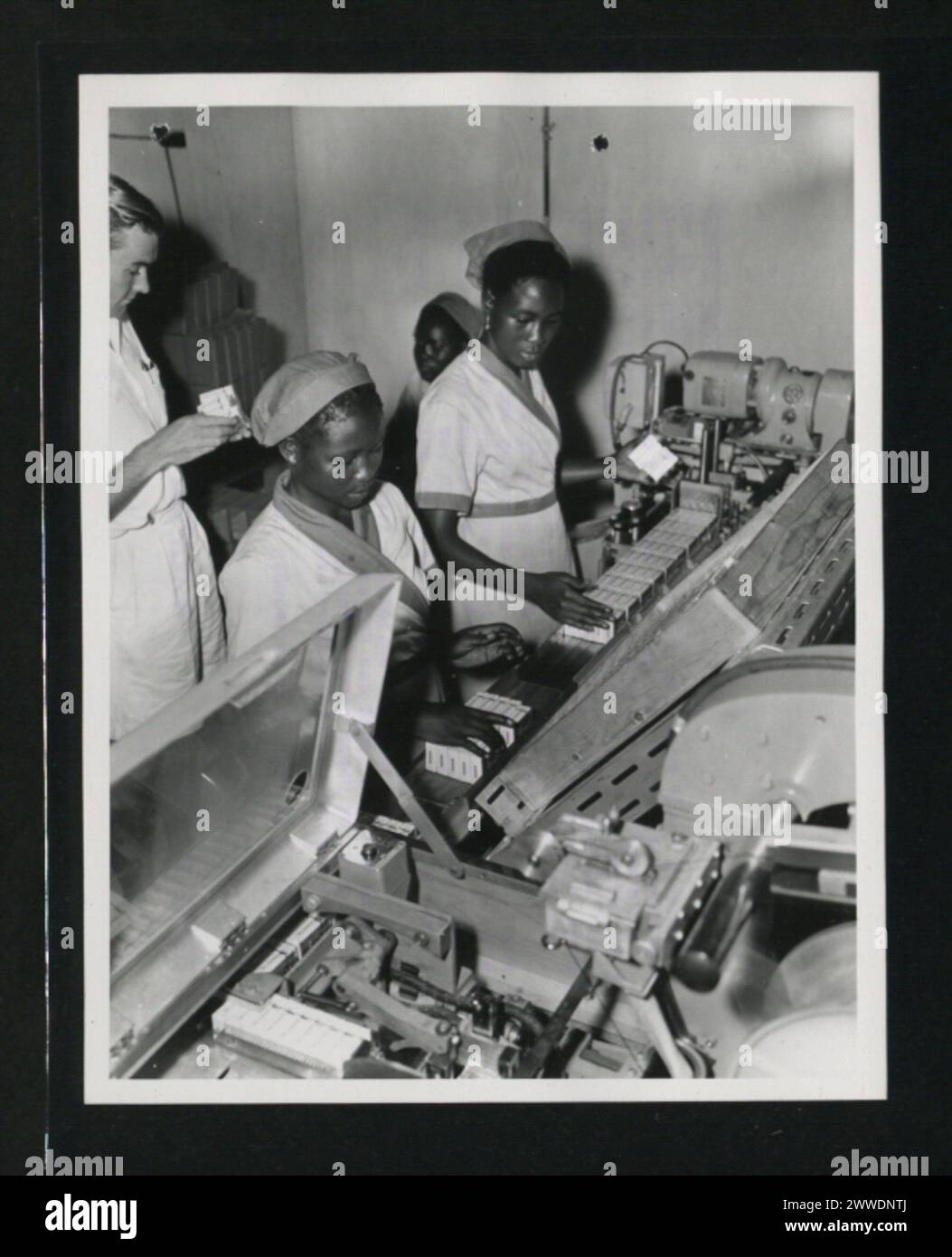 Description: Girls package cigarettes in a factory in Takoradi. Using ...
