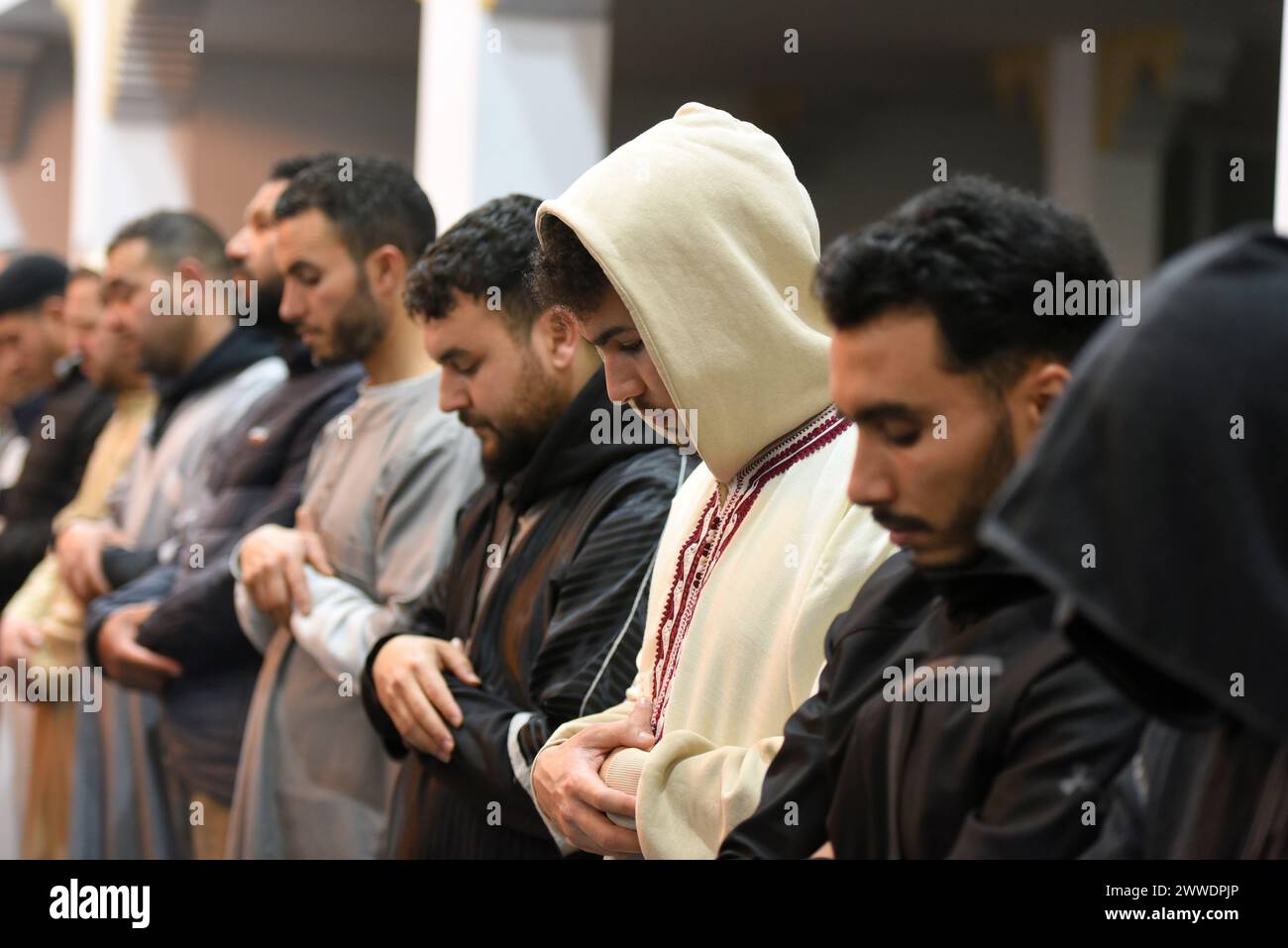 Several Muslim men pray standing with their arms crossed during the ...