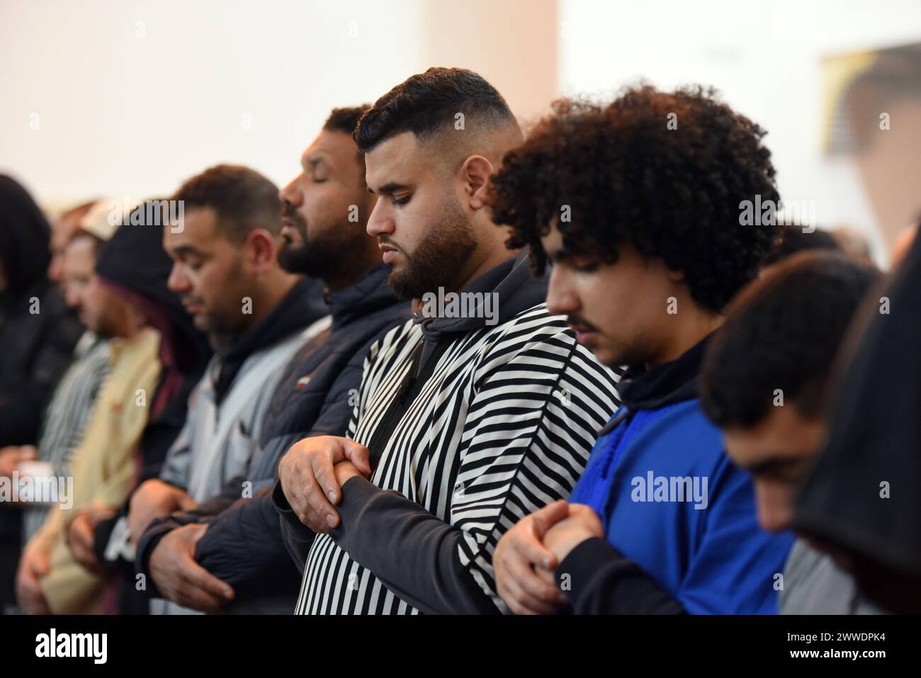 Several Muslim men pray standing with arms crossed (Qiyam) during the ...