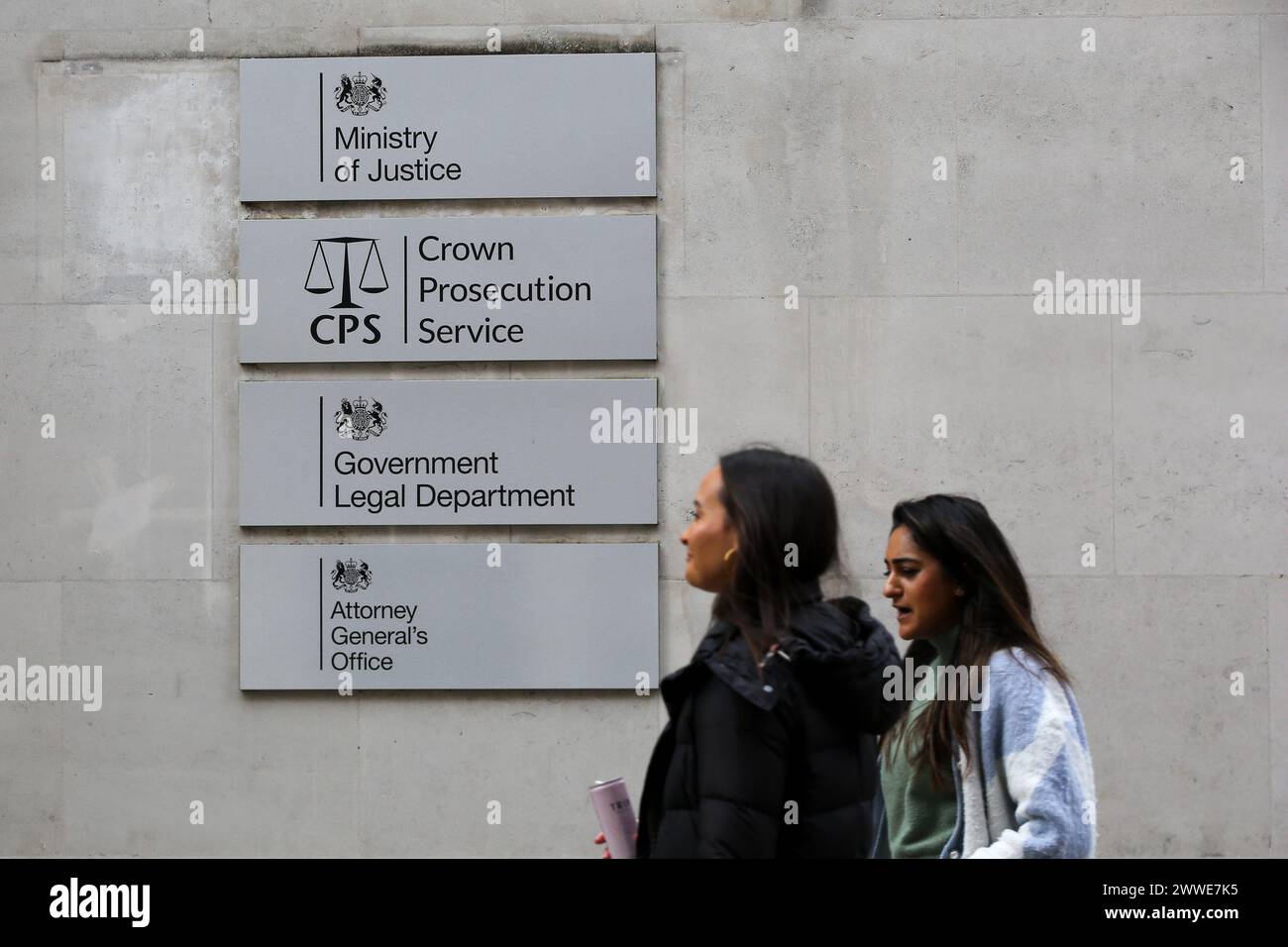 Women walk past the signs outside 102 Petty France in Westminster ...