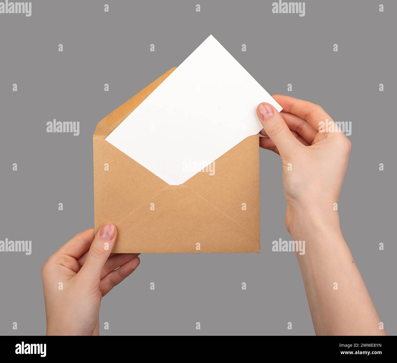 Holding open kraft envelope with white blank card inside, postcard ...