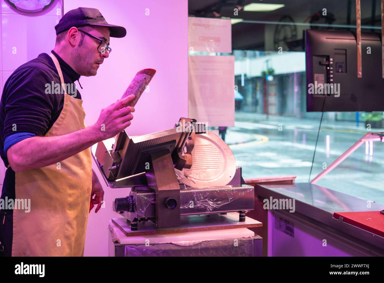 In this image, a butcher is showing a pork loin to a customer, ready to ...