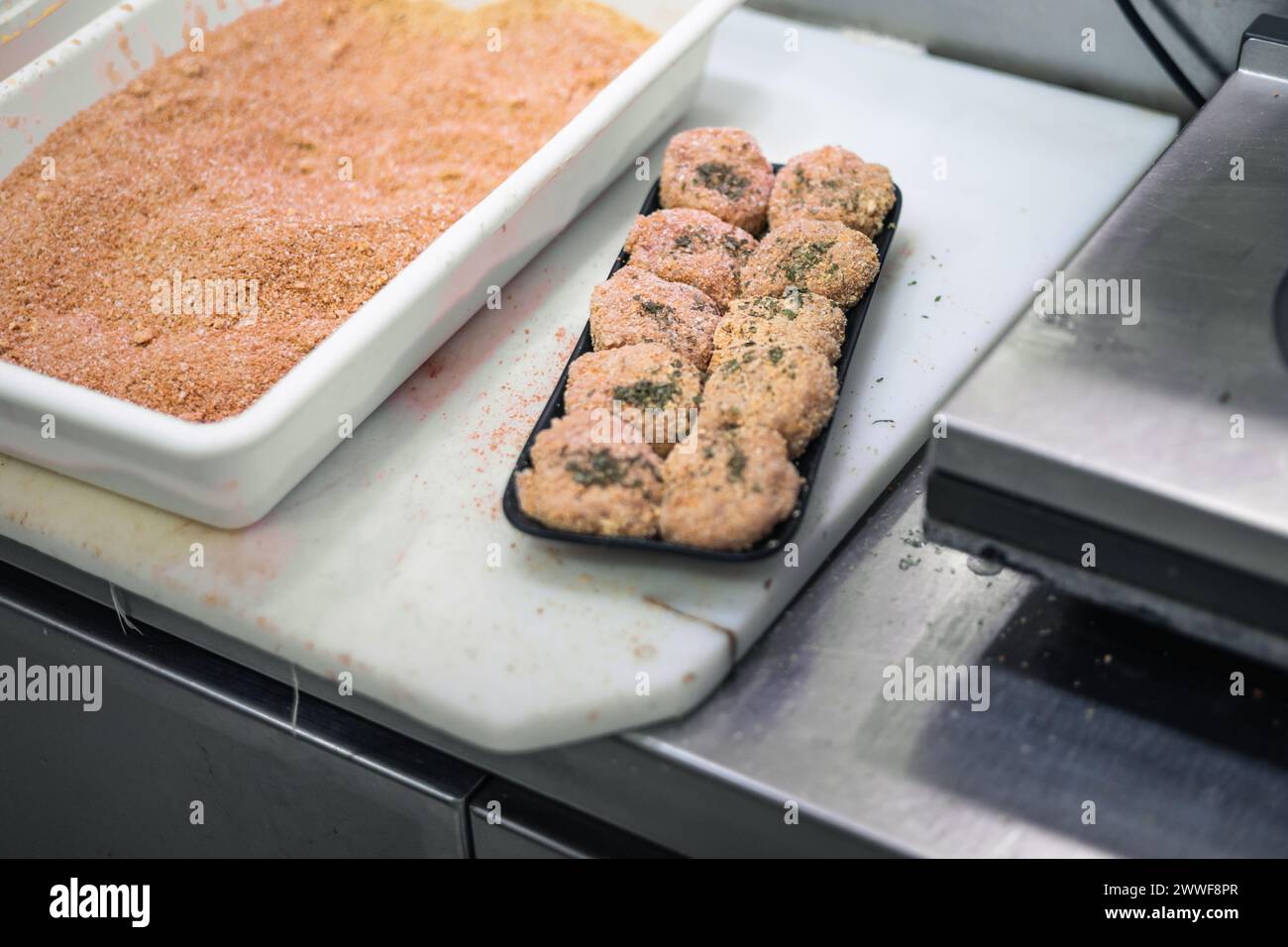 closeup of freshly breaded and prepared chicken nuggets, ready to be ...