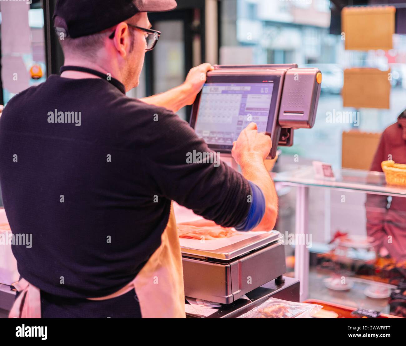 A cashier, seen from behind, is processing a customer's purchase using ...