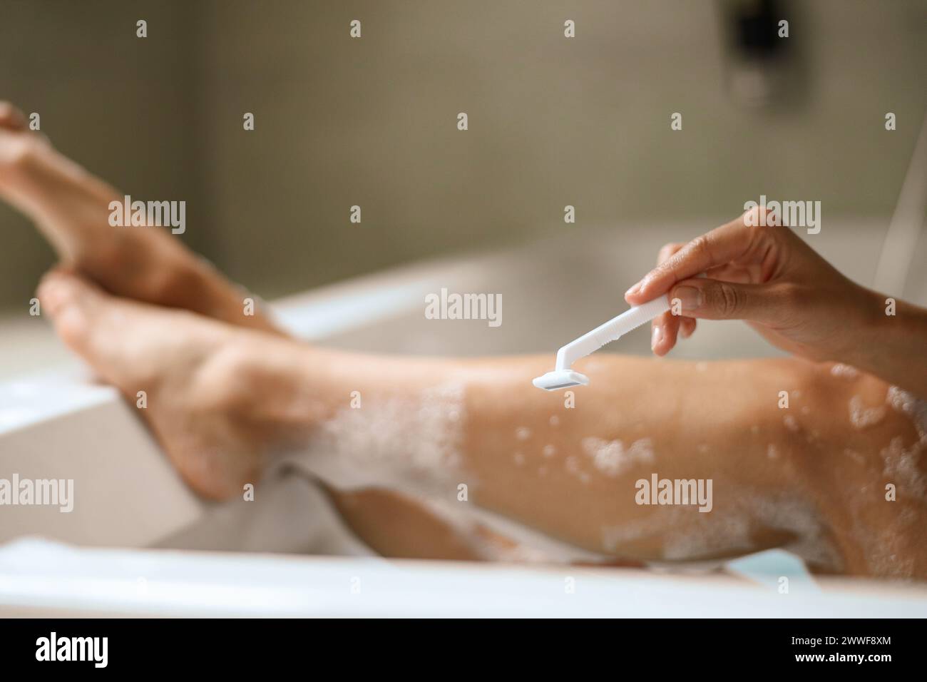 A woman is using a razor to shave her legs in a bathtub Stock Photo - Alamy