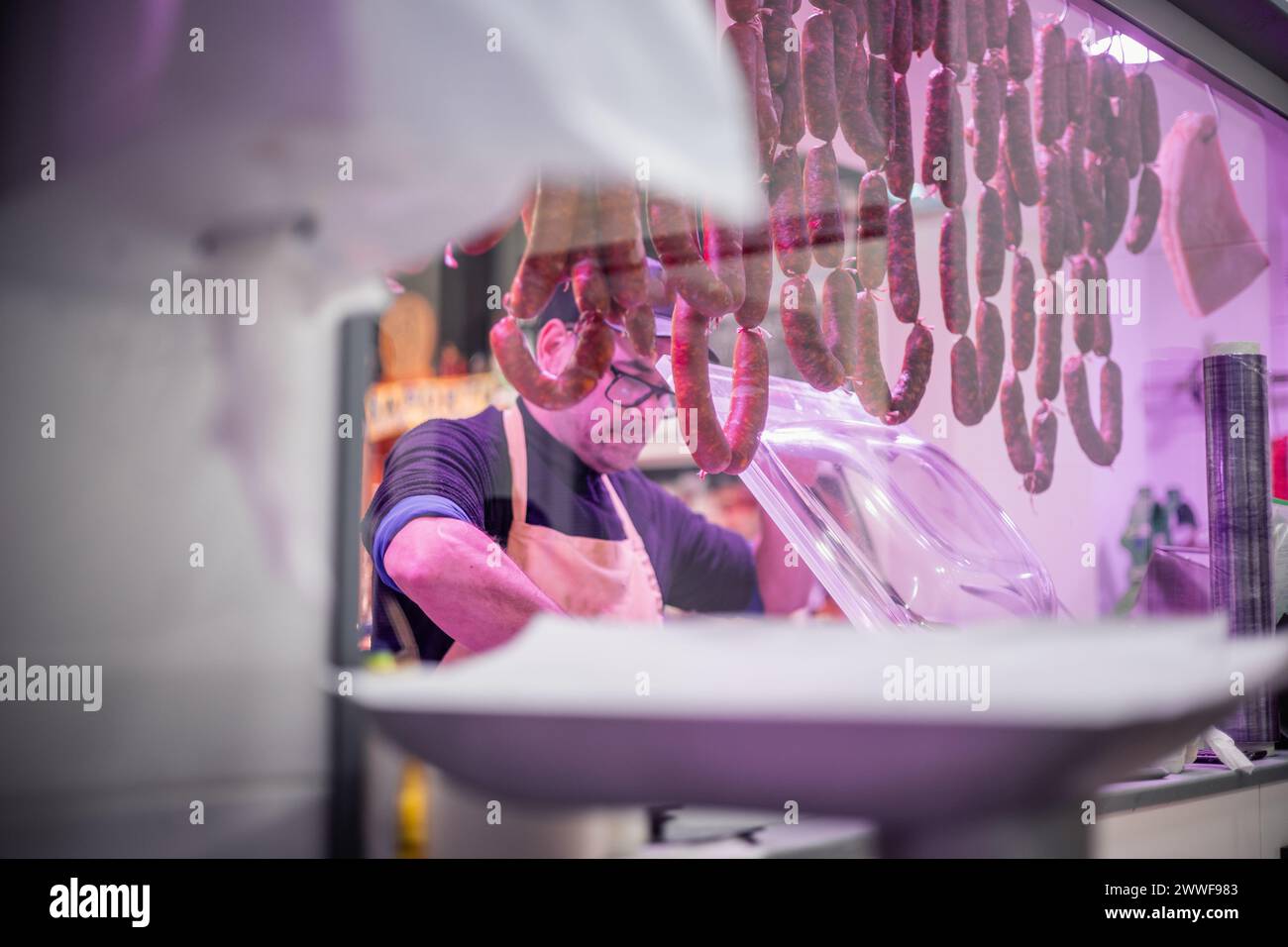 a butcher using a vacuum sealing machine while sausages and chorizos ...