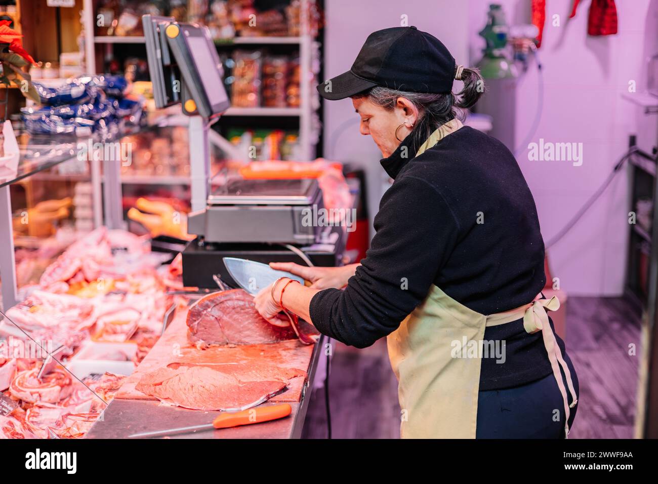 female butcher slicing a beef fillet with a knife on the counter of her ...