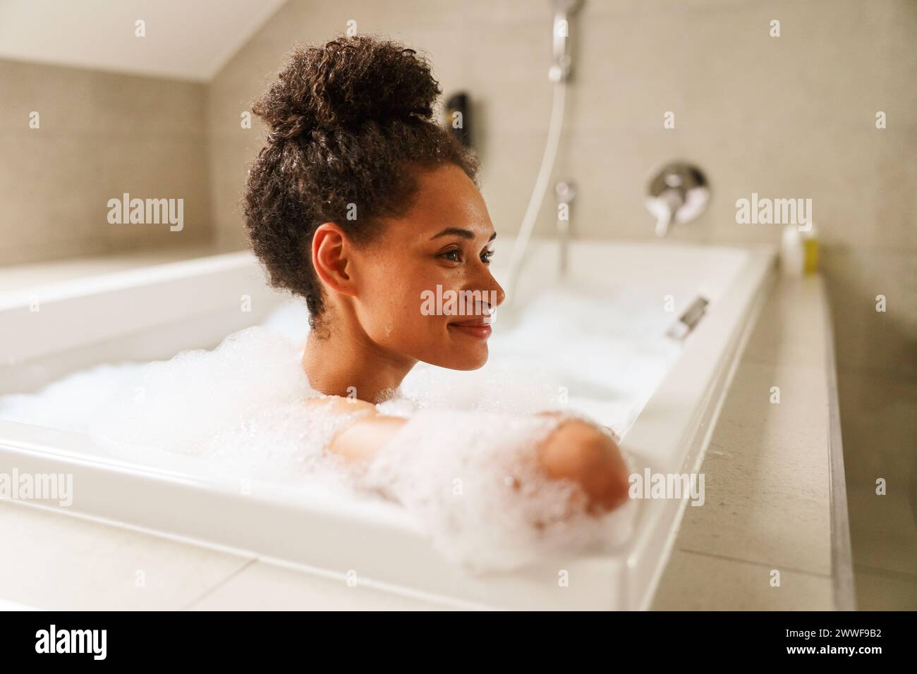 A woman happily bathing in a foamfilled bathtub in a bathroom Stock ...