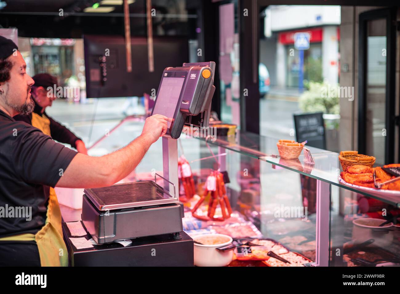 copyspace butcher using a scale at the butcher shop counter, with a ...