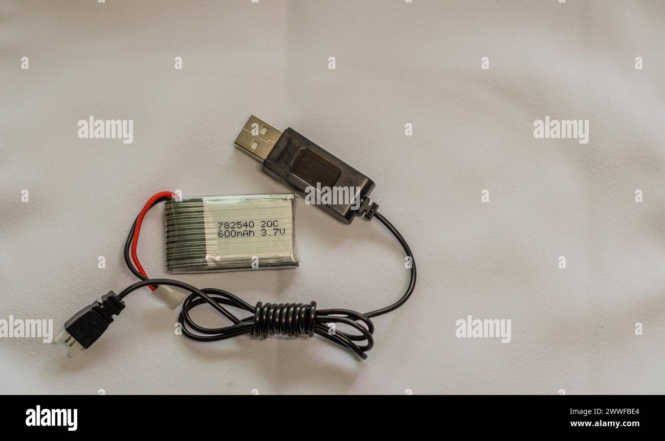 A USB cable connected to a lithium polymer battery on a white surface ...