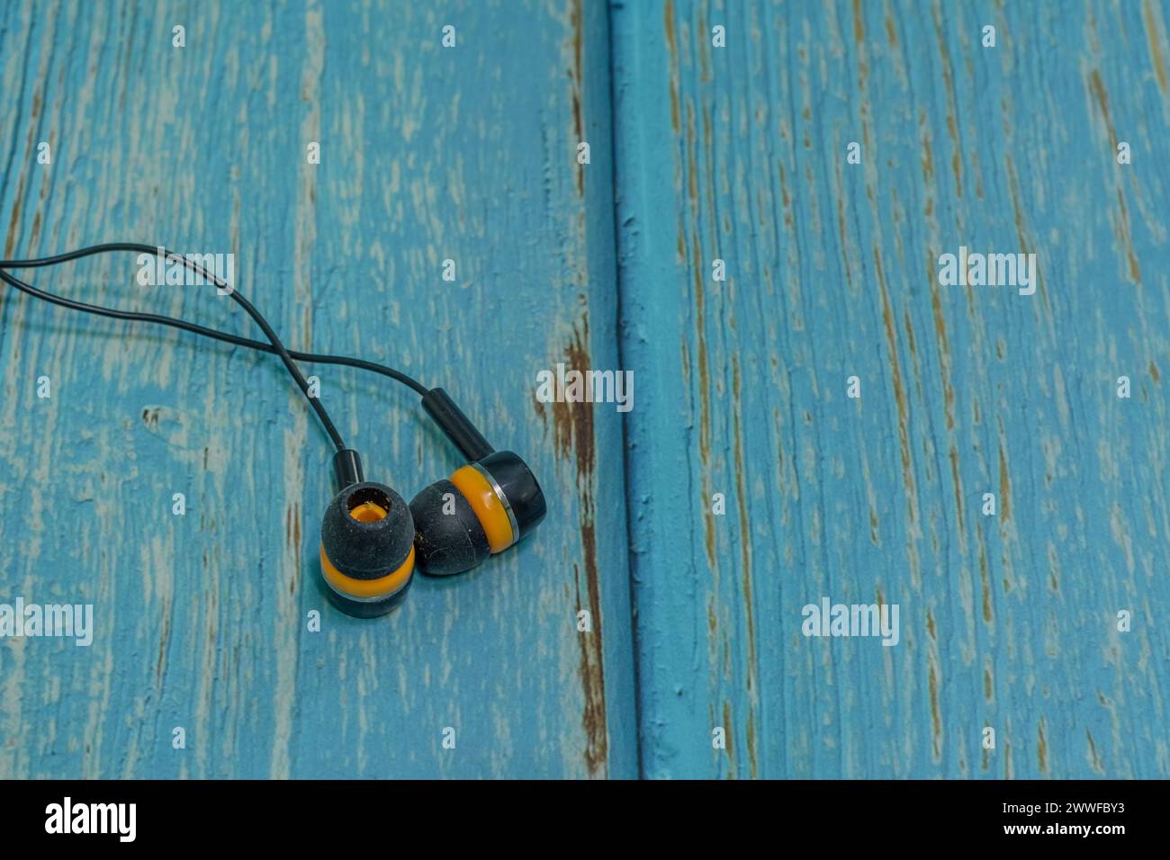 Set of black and yellow used ear buds on blue wood grain background ...