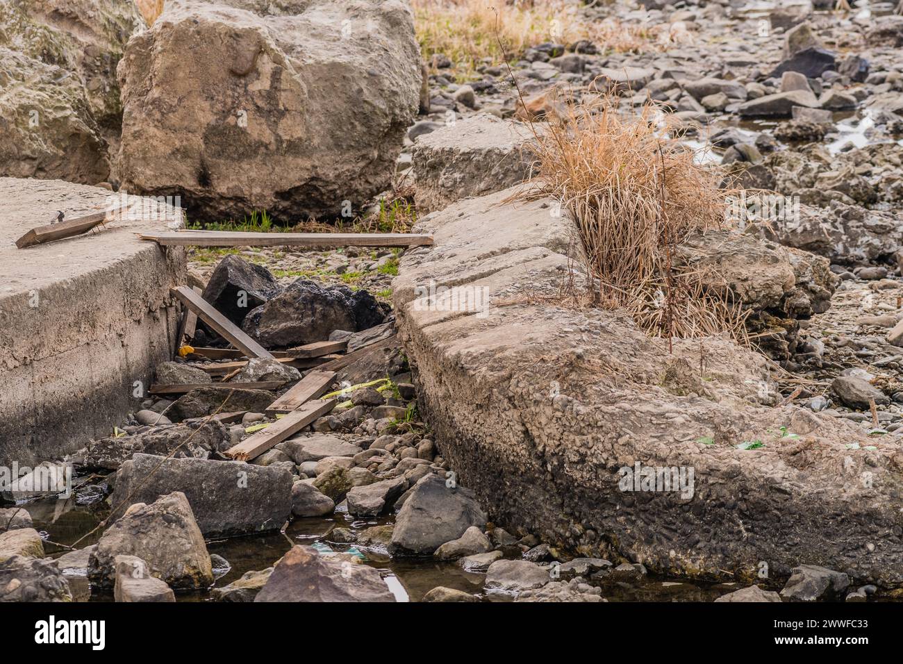 Dry stream bed showing damaged concrete structures and scattered rocks ...