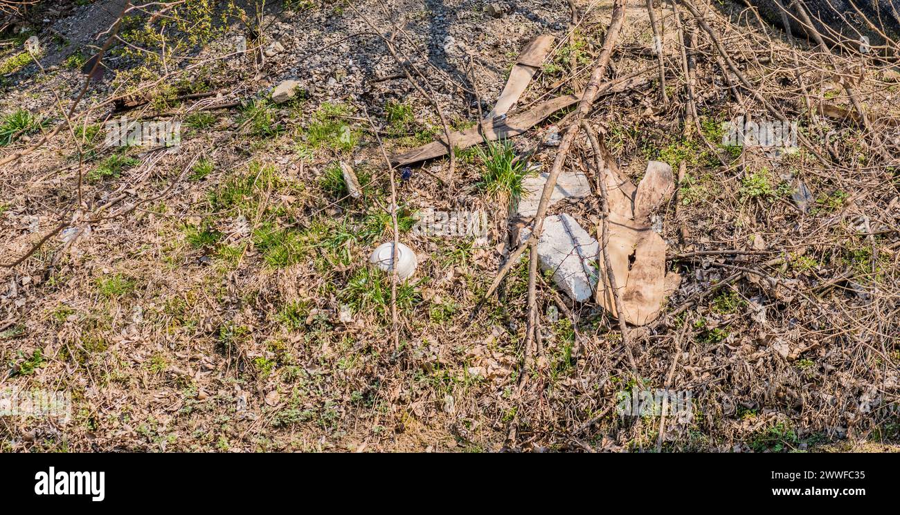 Discarded plastic and debris in a dry grassy area indicating ...