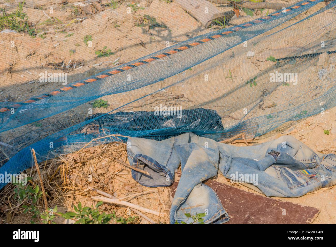 Abandoned clothing and construction net against dry soil depicting ...