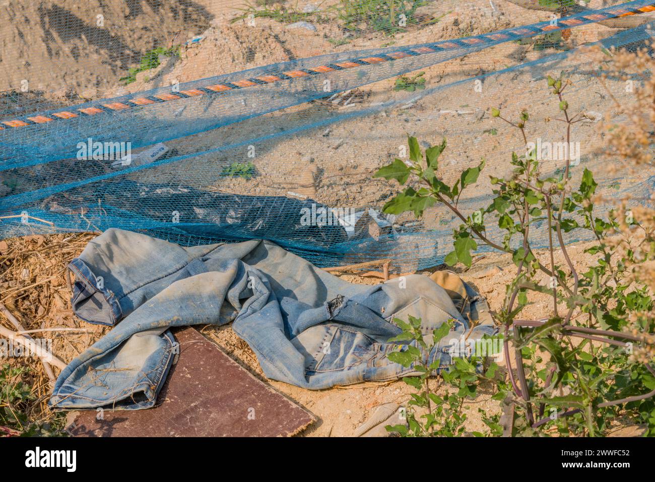 Pile of cast-off clothes and torn erosion net on natural ground ...