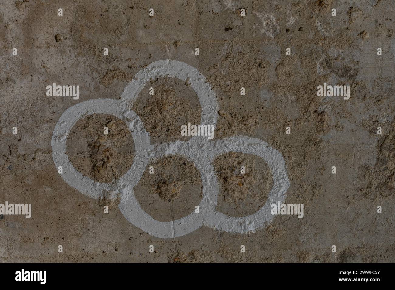 Simple graffiti of three interlinked rings on a rough concrete wall, in ...