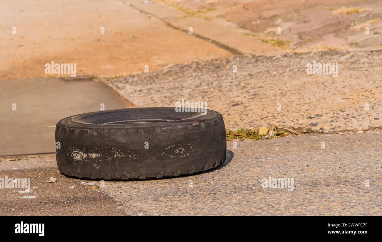 A used tire with drawings left on urban pavement, portraying a waste ...