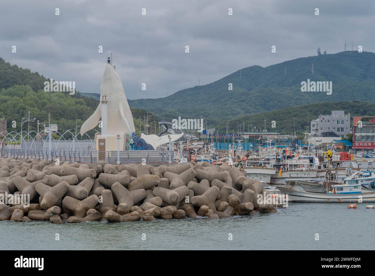 Harbor view with a white lighthouse, docked boats, and tetrapod ...