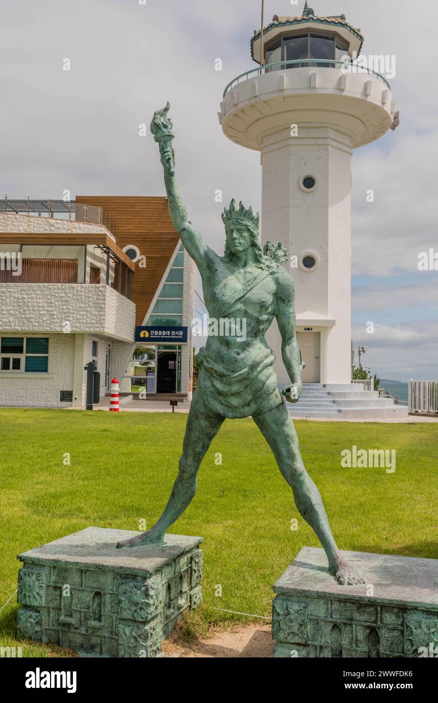 Statue in a hero pose with a lighthouse and a dramatic sky in the ...