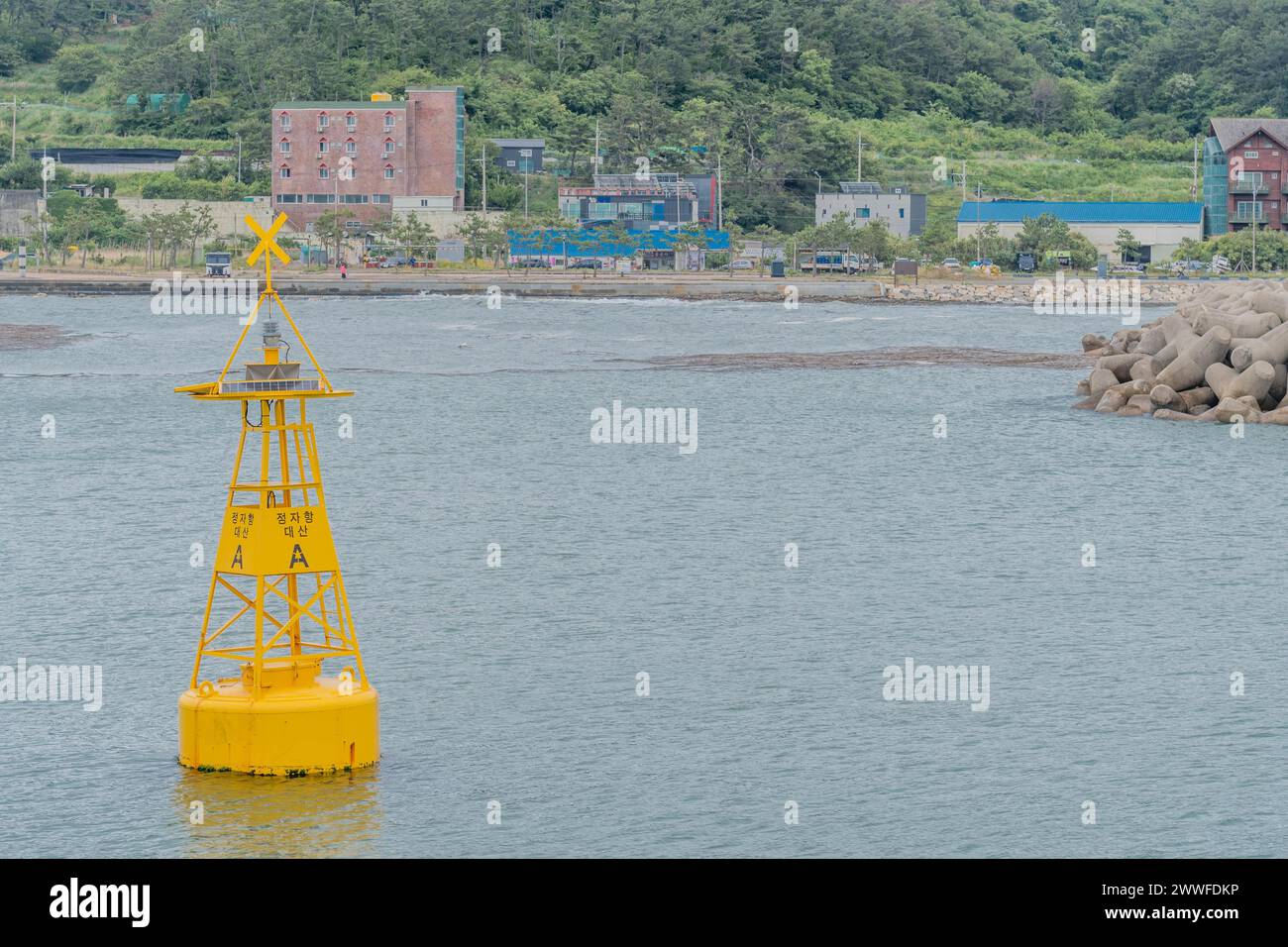 A yellow navigation buoy bobs in the ocean under a cloudy sky, marking ...