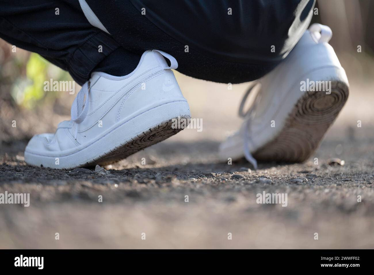 White trainers of an athletically dressed boy, crouched posture, on a ...