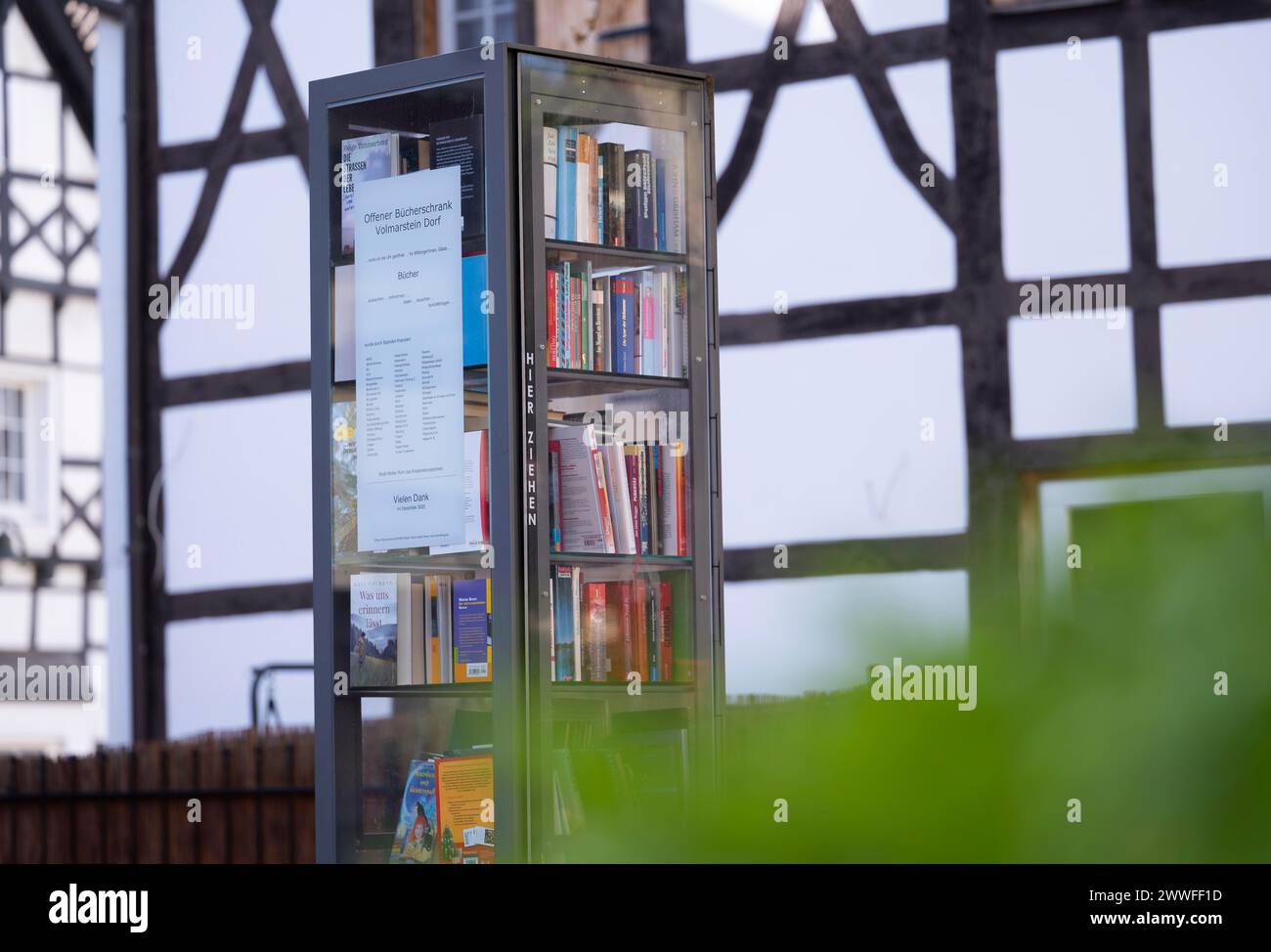 Open bookcase in front of half-timbered house and fence, many colourful ...