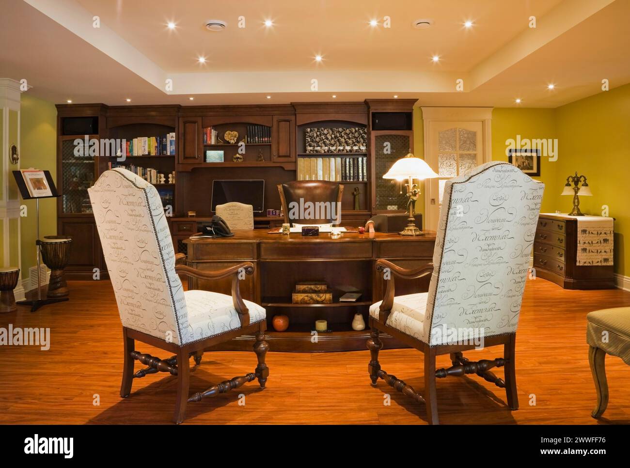 Wooden desk, high back chairs and wall unit in basement home office ...